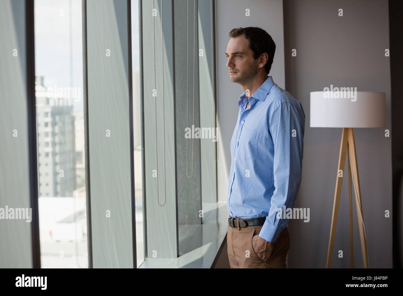 Thoughtful male executive looking through window in office Stock Photo ...