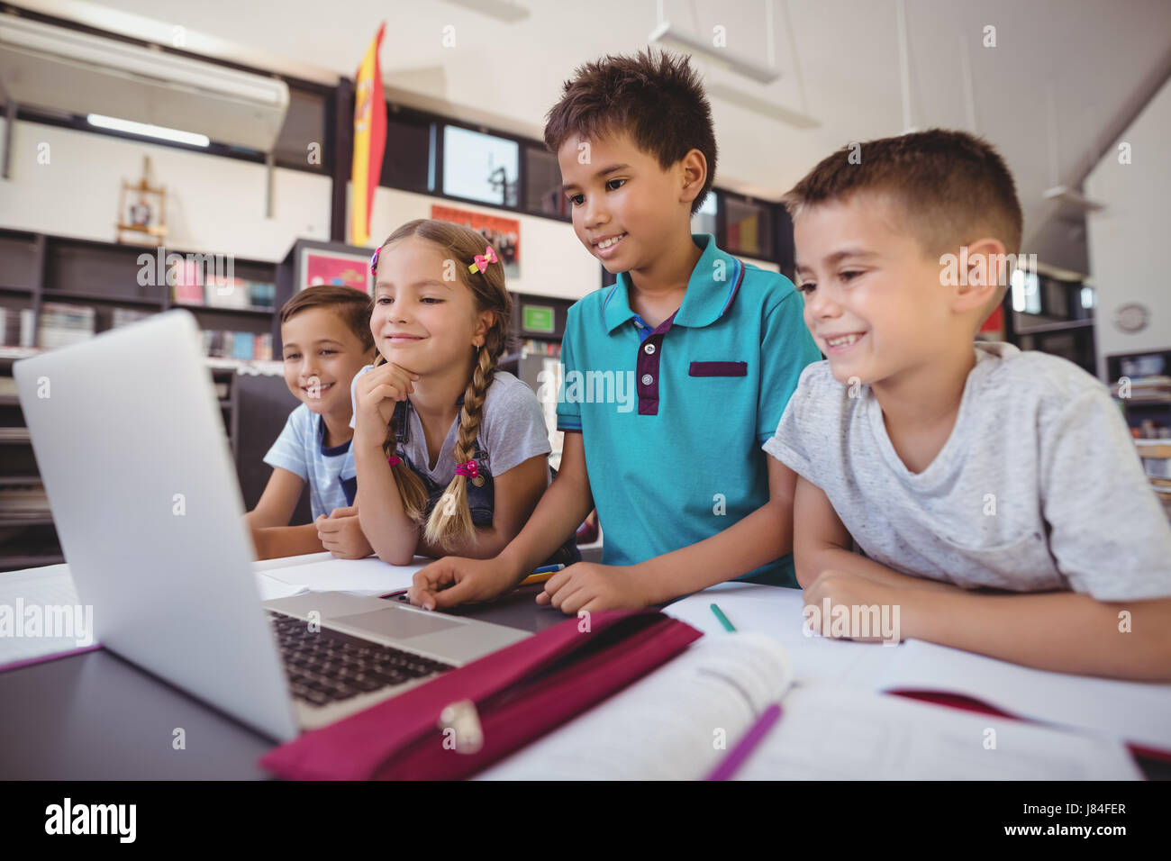 Happy schoolkids using laptop in library at school Stock Photo - Alamy