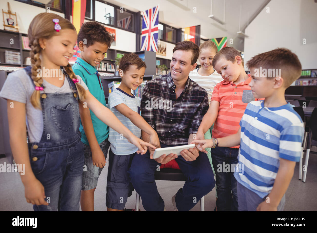 Teacher and schoolkids using digital tablet in library at school Stock ...
