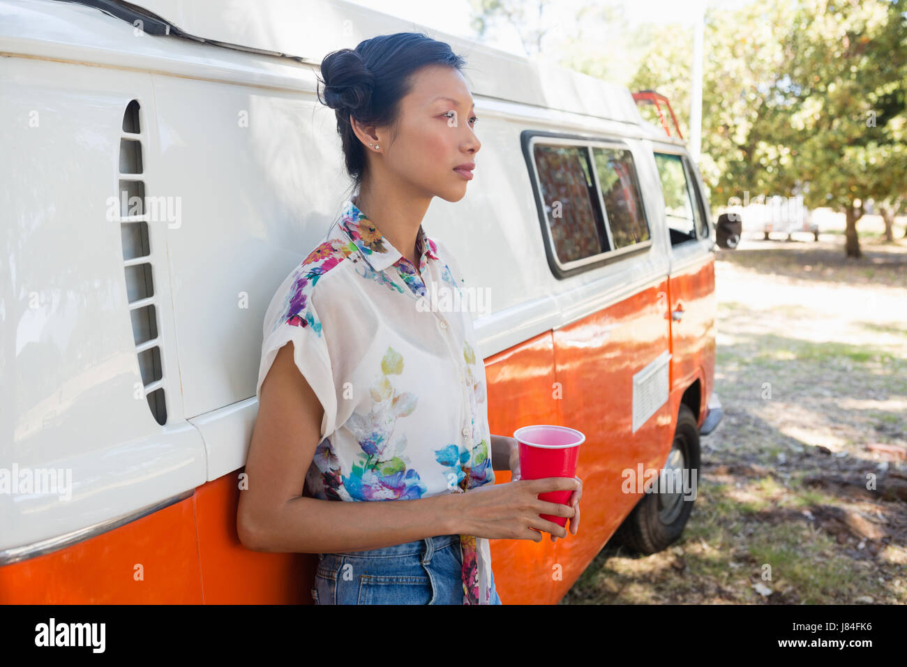 Young woman leaning on camper van in the park Stock Photo - Alamy
