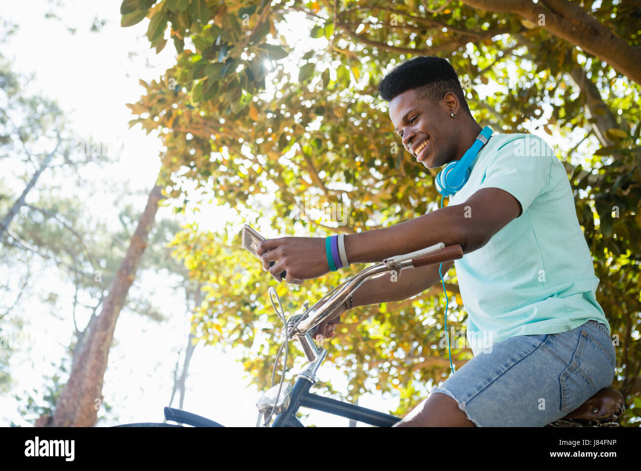 Man using mobile phone while riding his bicycle in the park Stock Photo ...