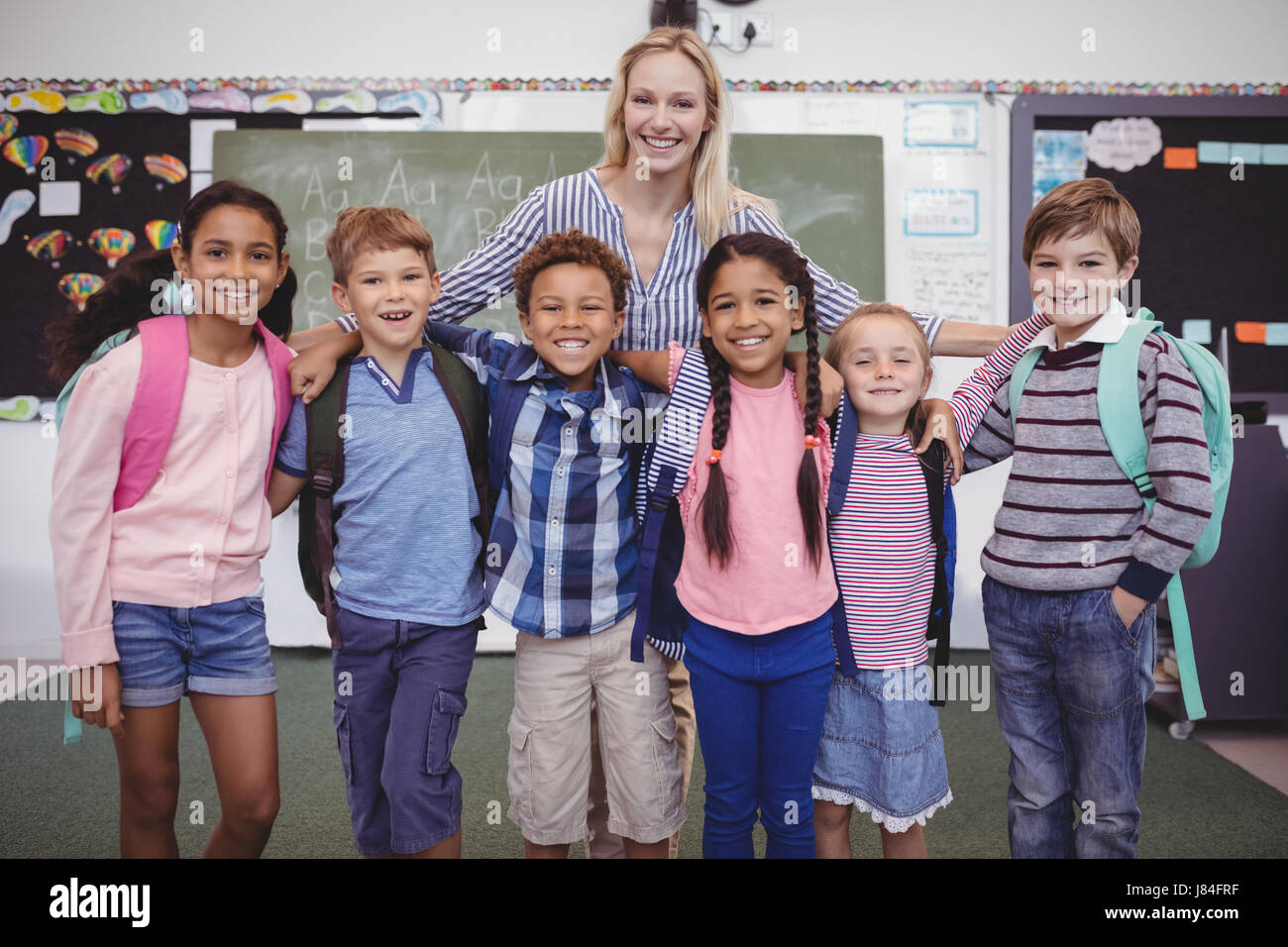 Happy teacher standing with schoolkids in classroom at school Stock ...