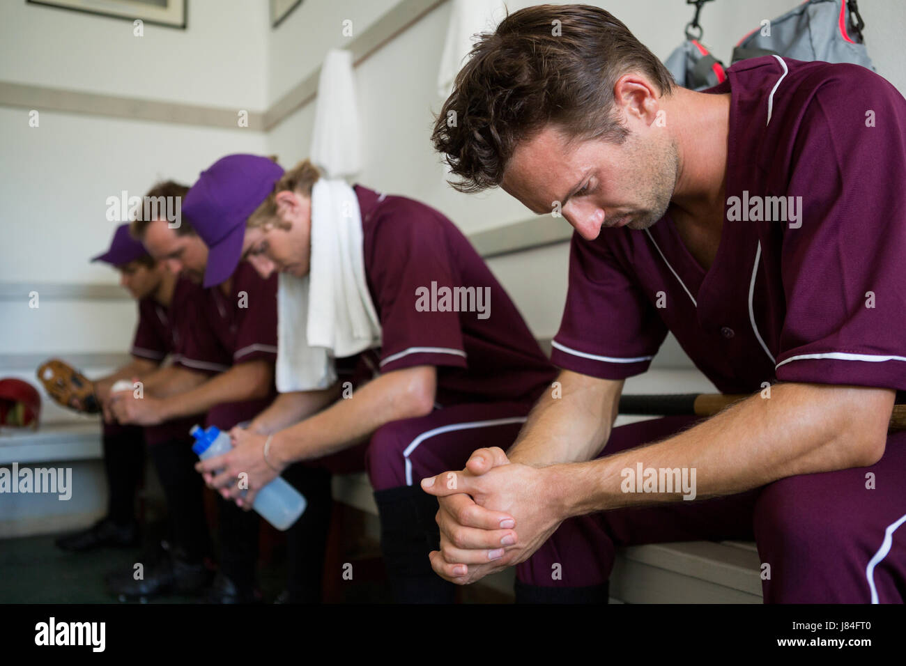 Close up of tired basball players sitting on bench at locker room Stock ...