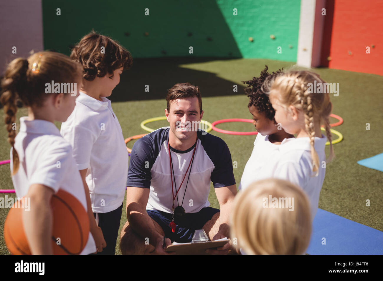 Happy coach with schoolkids in schoolyard Stock Photo - Alamy