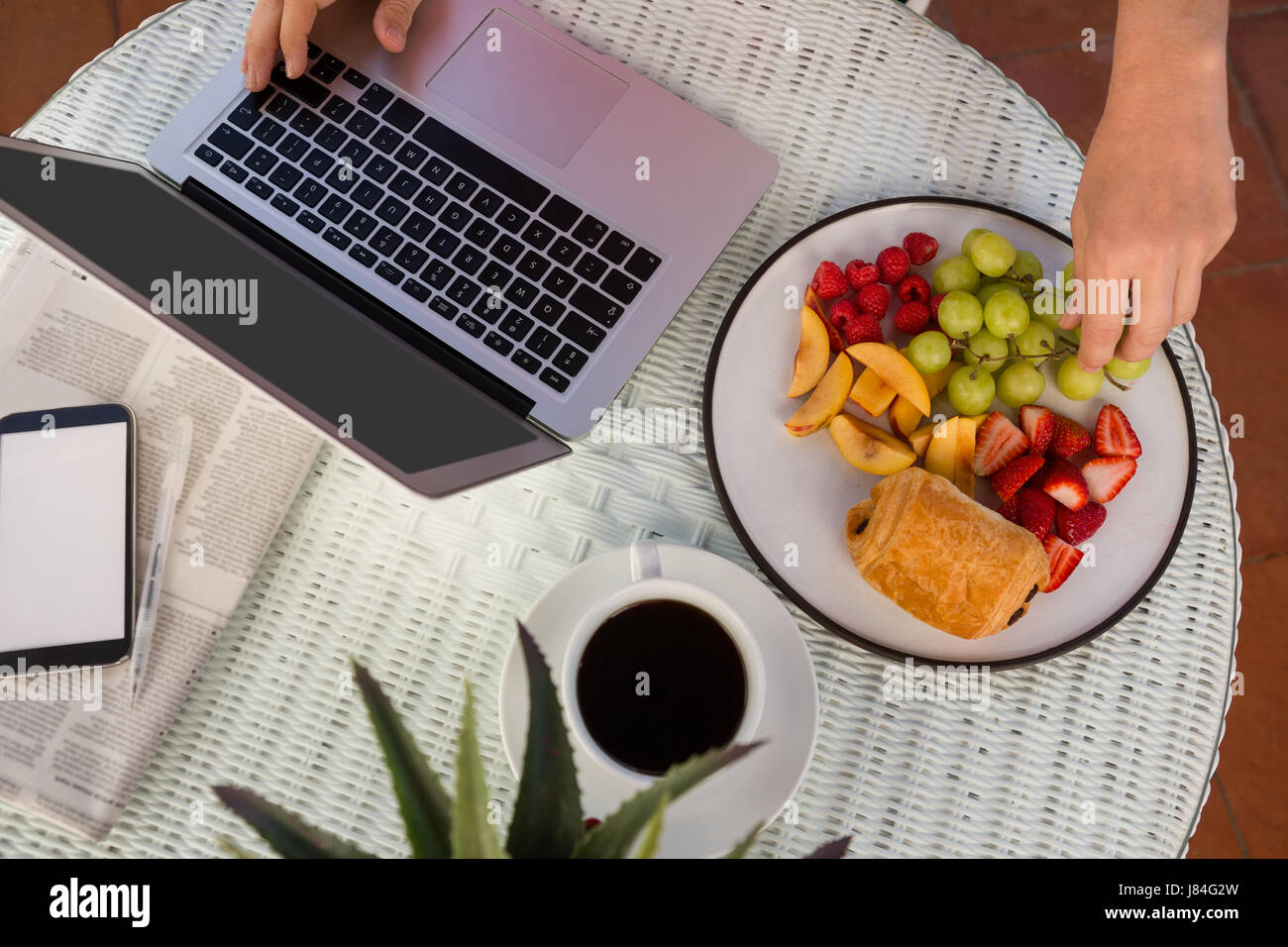 Cropped hands of person having fruit while using laptop on table Stock Photo - Alamy