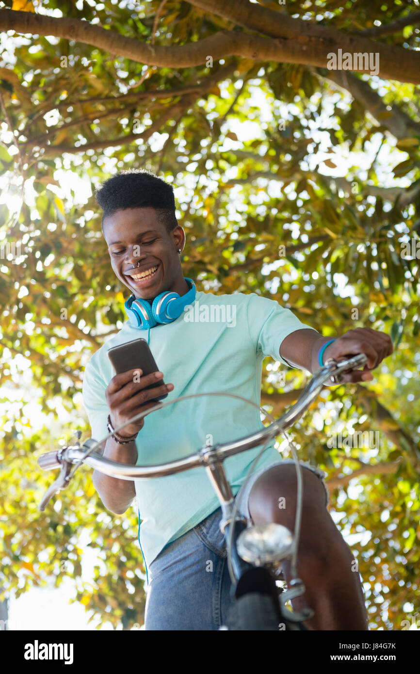 Man using mobile phone while riding his bicycle in the park Stock Photo ...