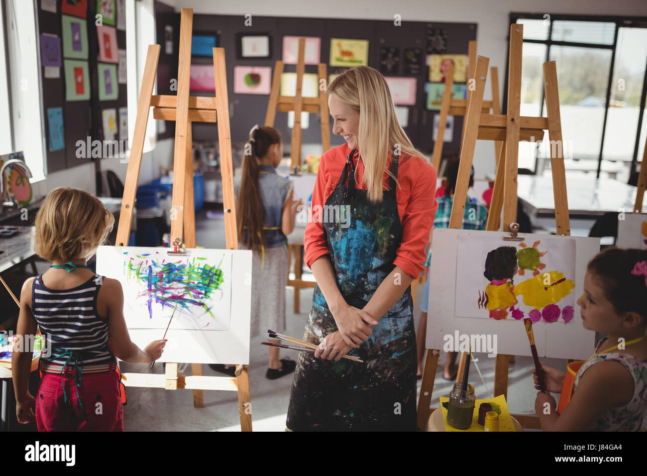 Teacher assisting schoolkid in drawing class at school Stock Photo - Alamy