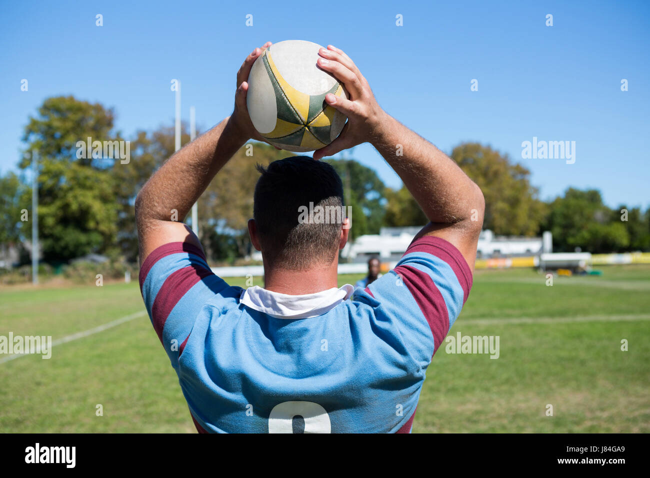 Rear view of player standing with rugby ball on field Stock Photo - Alamy