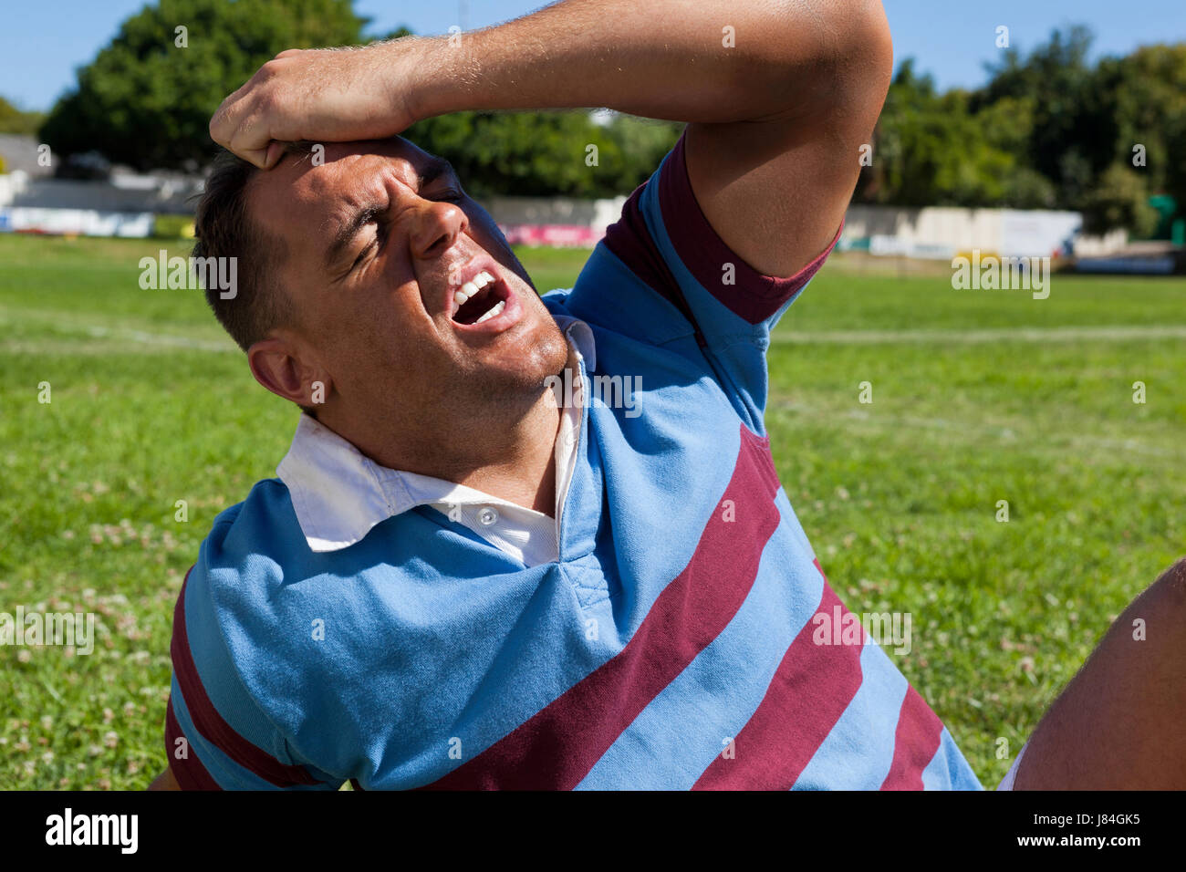 Unhappy rugby player sitting on field during sunny day Stock Photo - Alamy