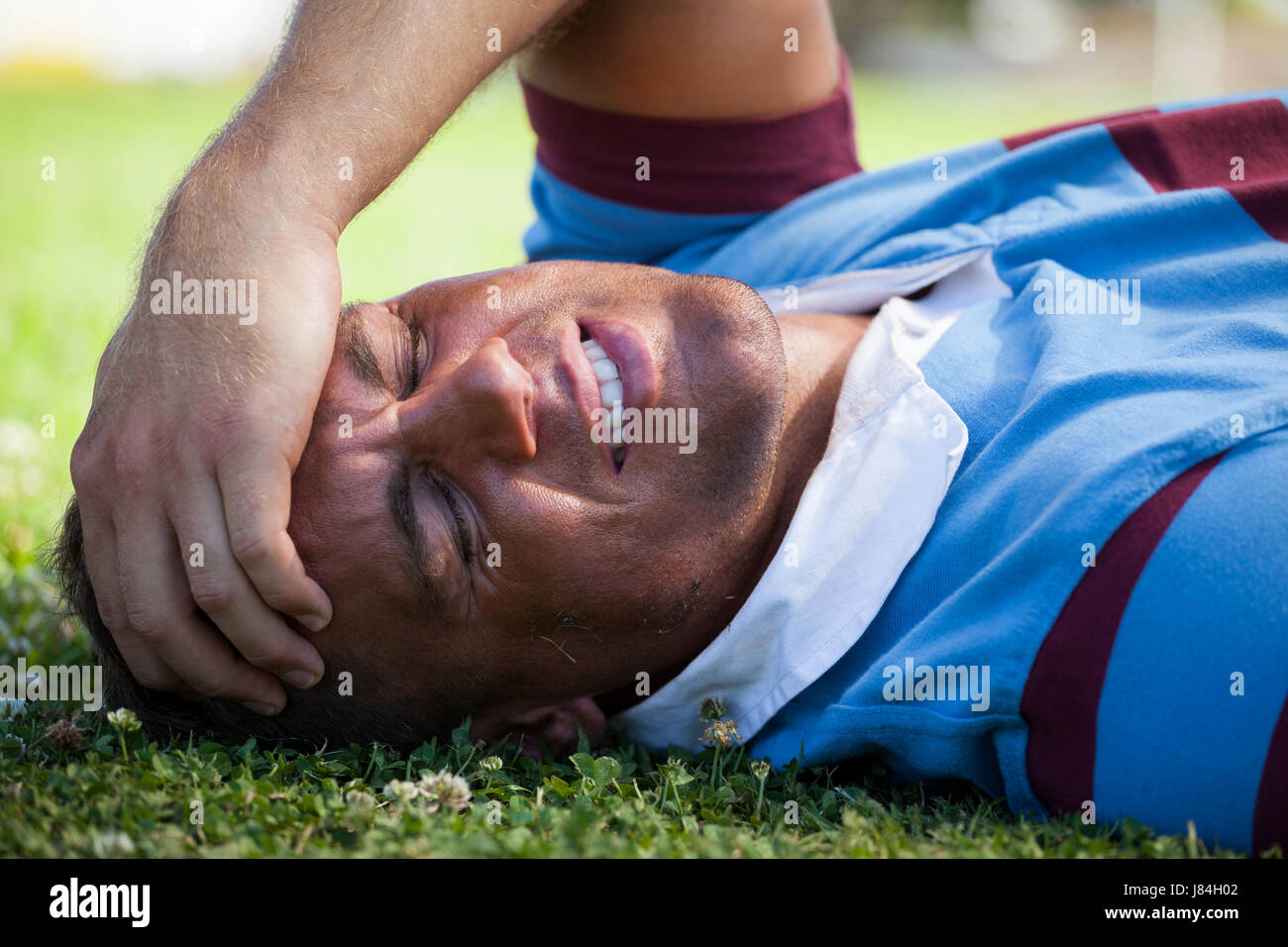 Injured rugby player with eyes closed lying on playing field Stock ...