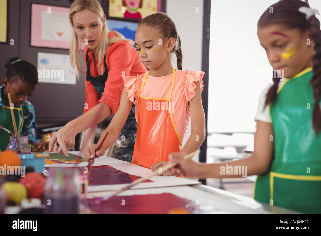 Teacher assisting schoolkids in drawing class at school Stock Photo - Alamy