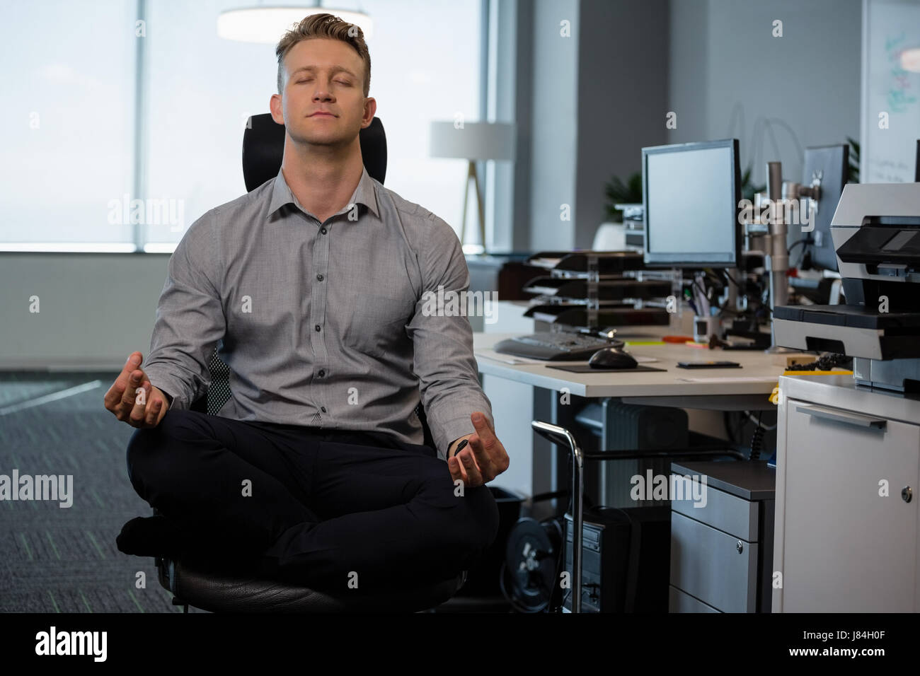 Executive meditating at desk in office Stock Photo - Alamy