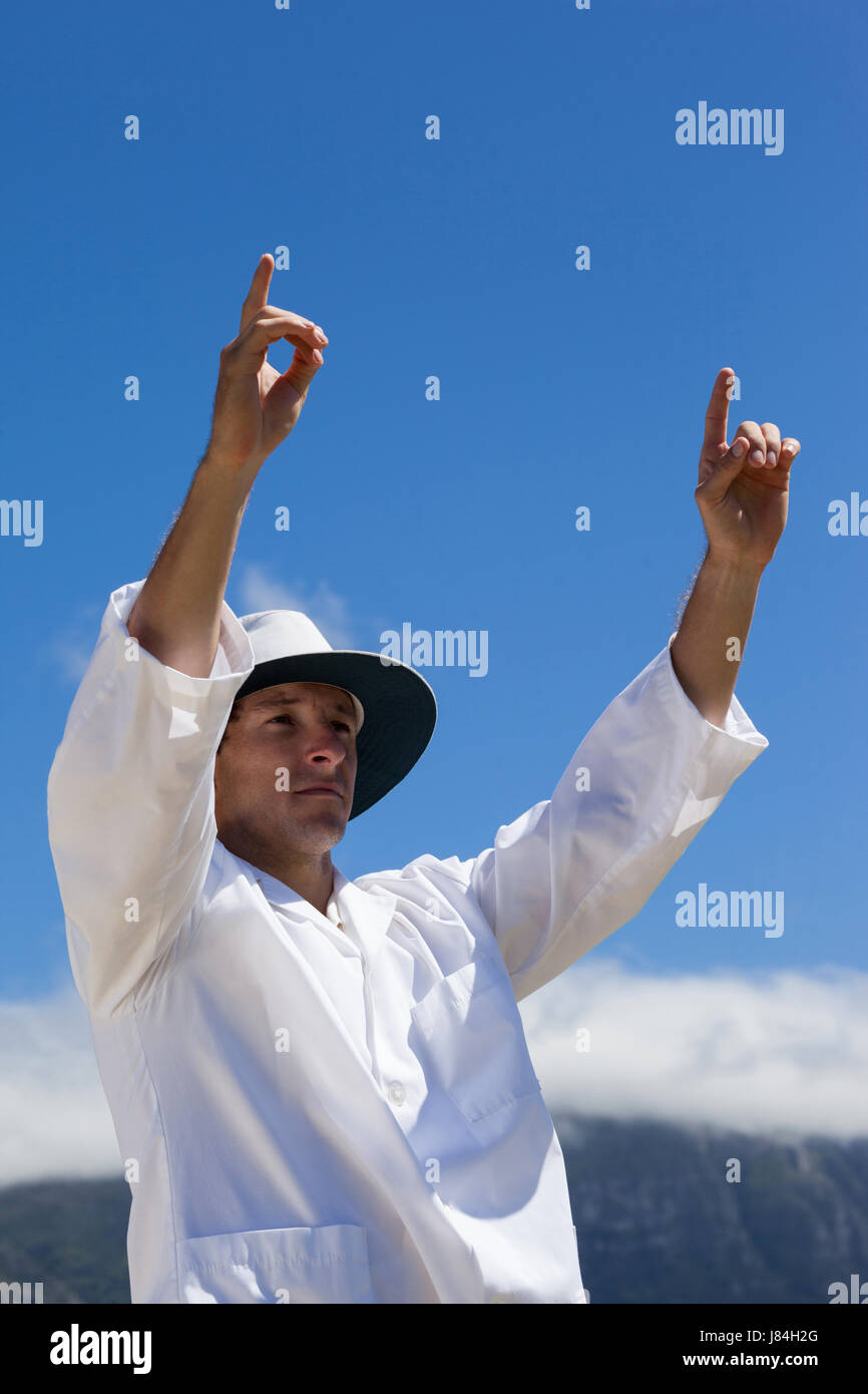 Low angle view of cricket umpire signalling six runs against blue sky ...