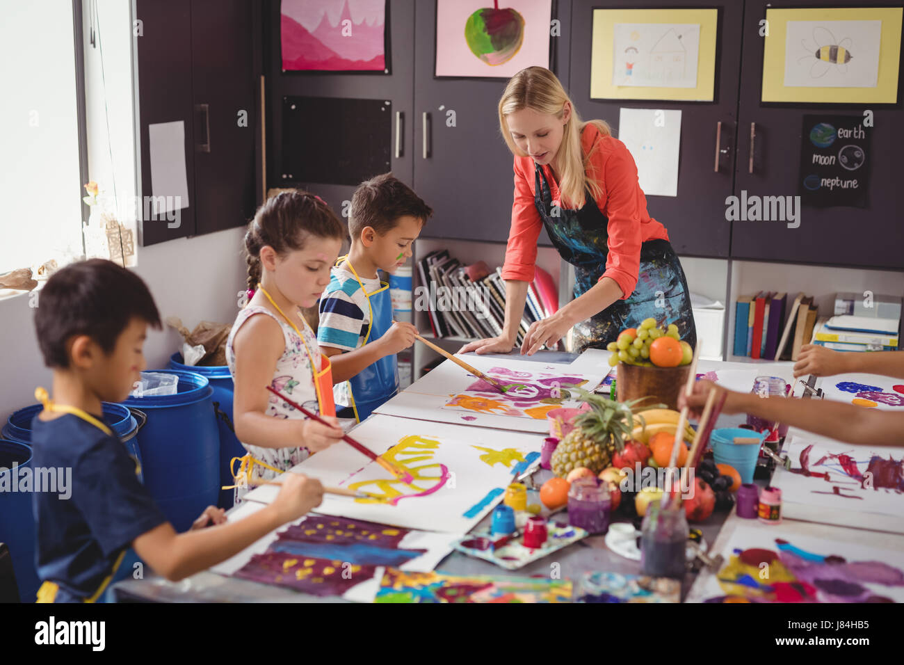 Teacher assisting schoolkids in drawing class at school Stock Photo - Alamy