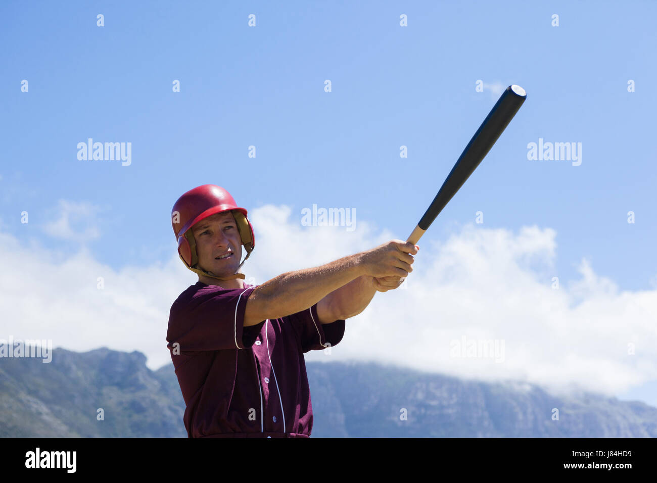 Baseball playing hitting with bat while standing against mountain and ...