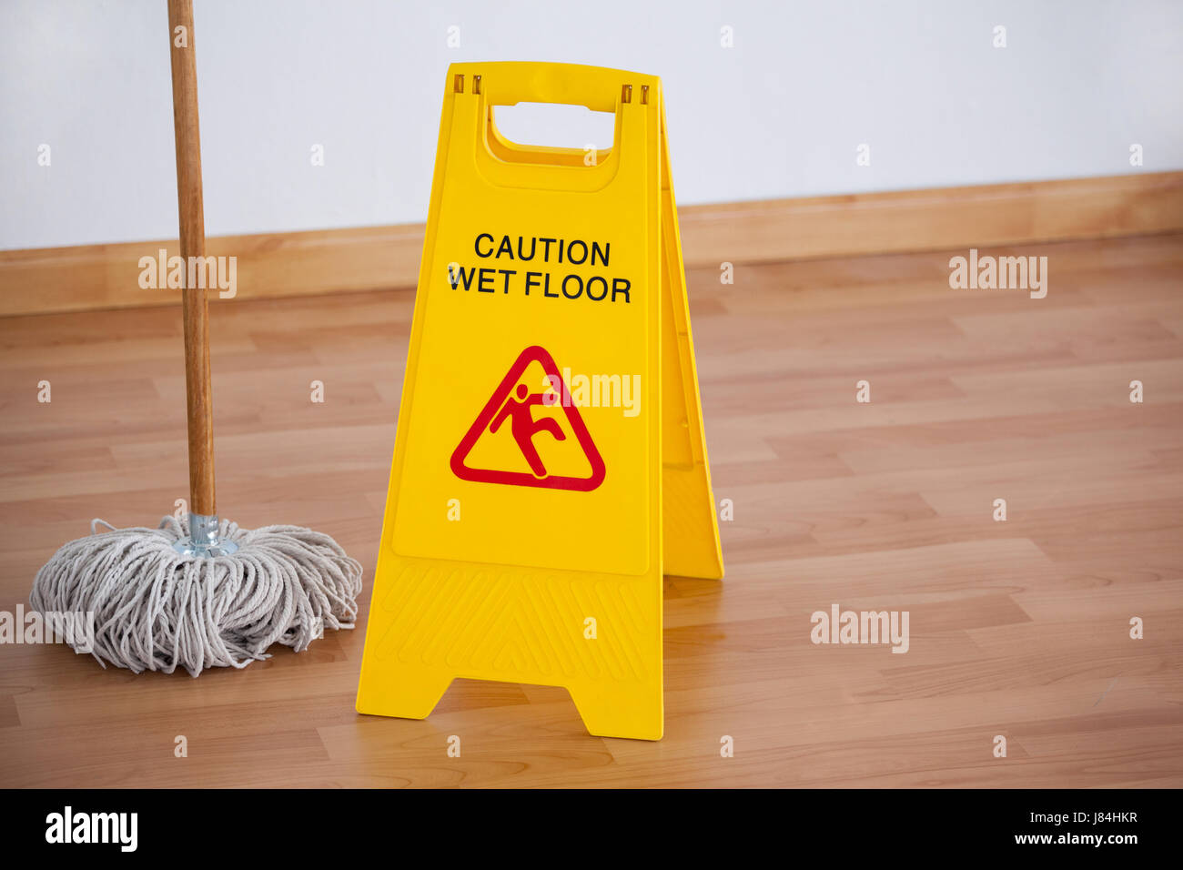 Mop with wet floor caution sign on wooden floor Stock Photo - Alamy