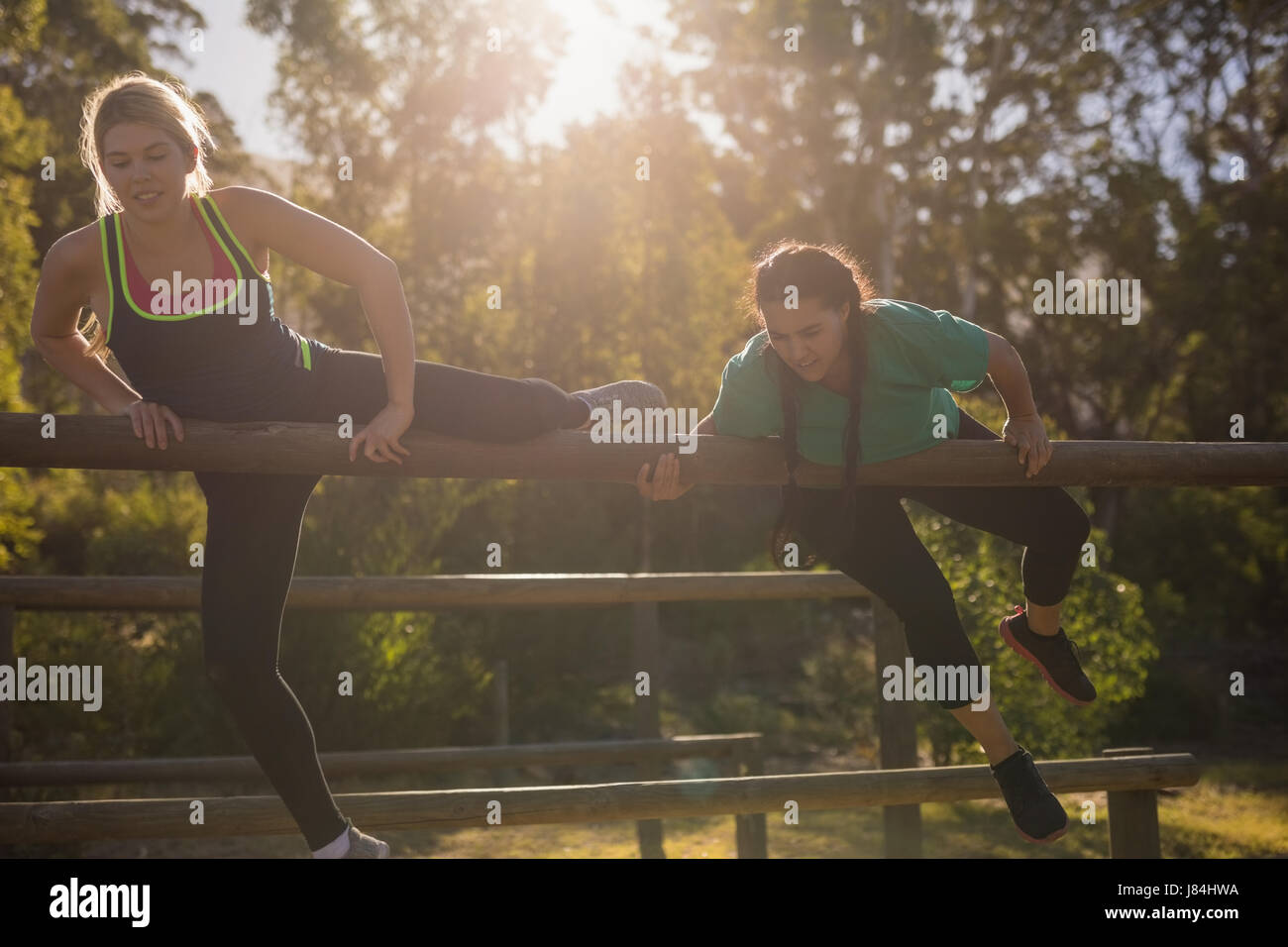 Women exercising on outdoor equipment during obstacle course in boot ...