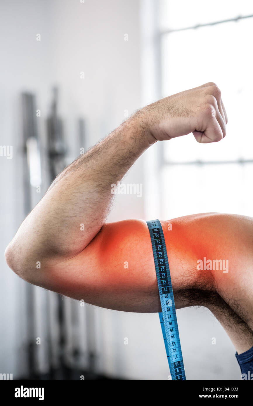 Digital composite of highlighted arm of man measuring biceps with ...