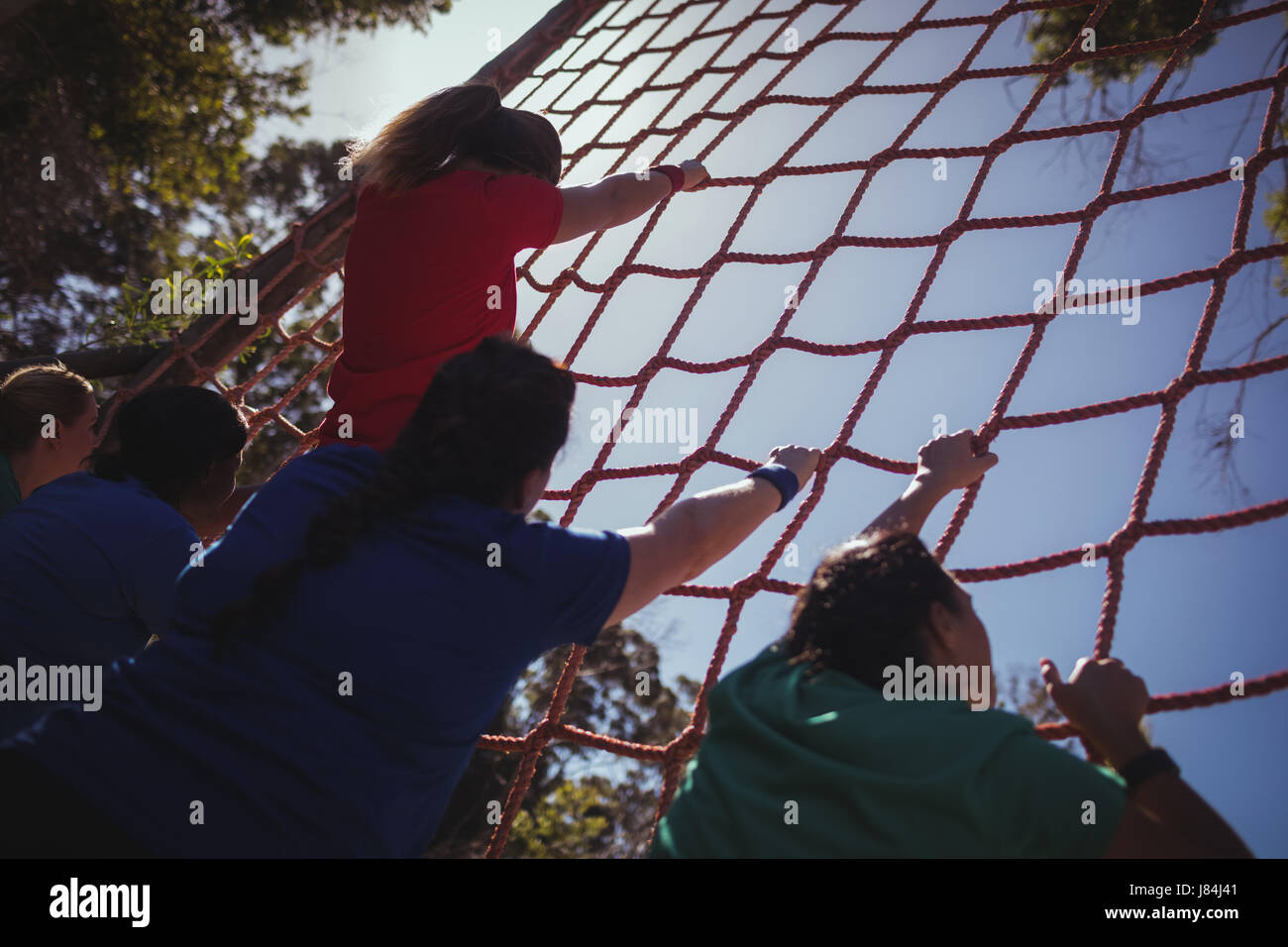 Group of fit woman climbing a net during obstacle course training in ...