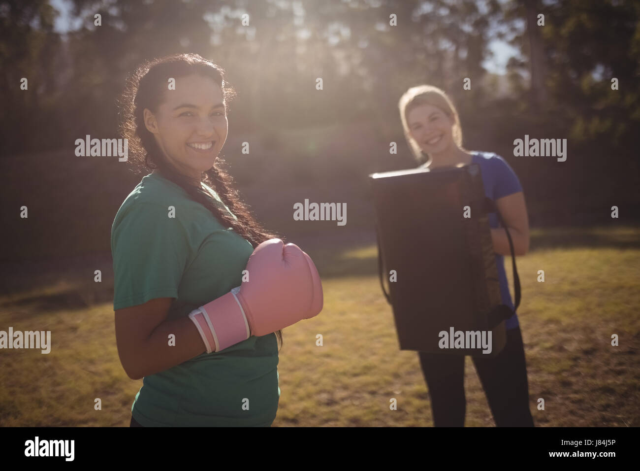 Portrait of happy woman wearing boxing gloves during obstacle course in ...