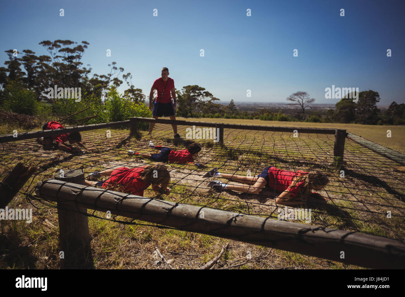 Kids crawling under the net during obstacle course training in the boot ...