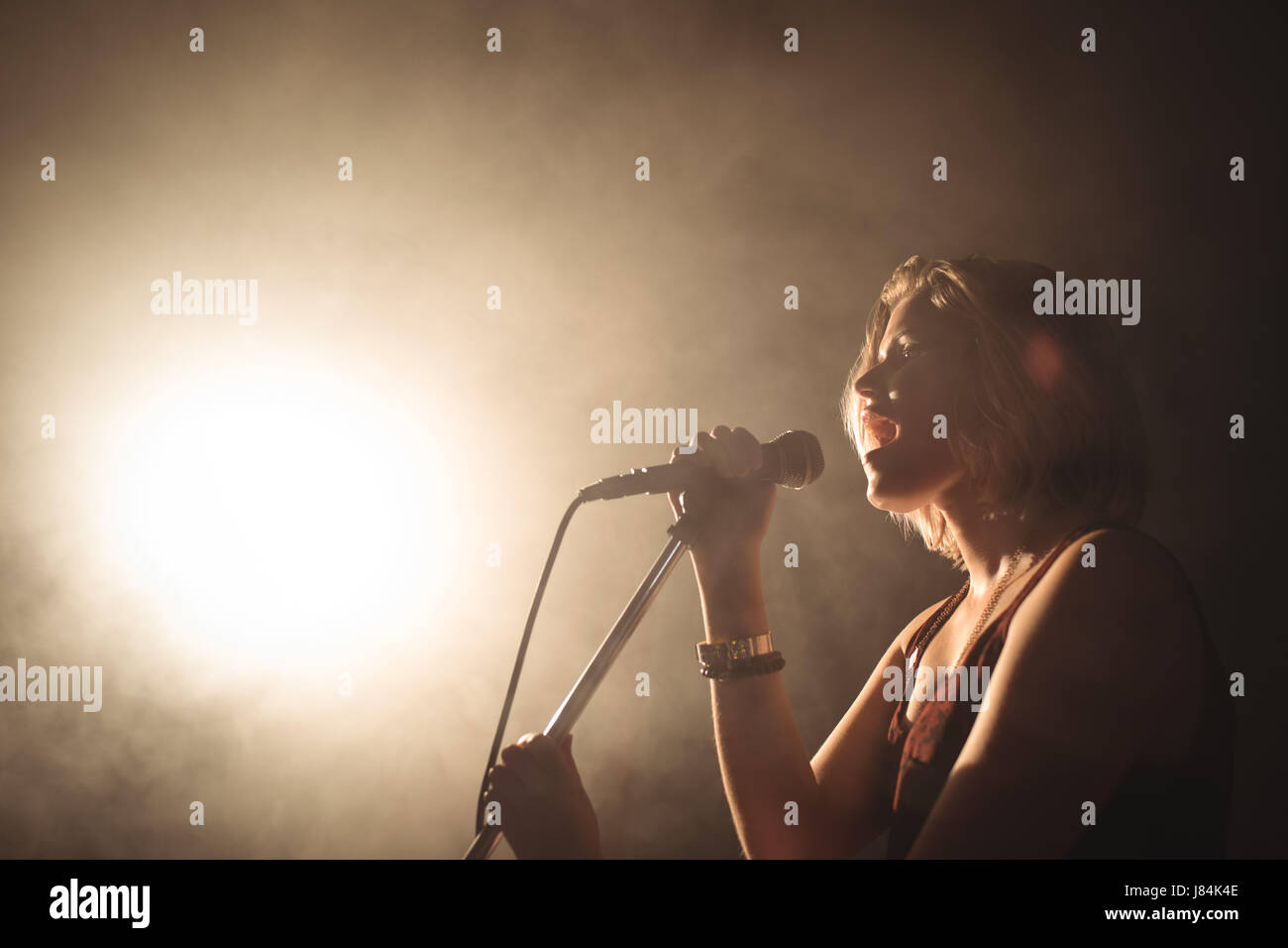 Low angle view of confident female singer performing in illuminated ...