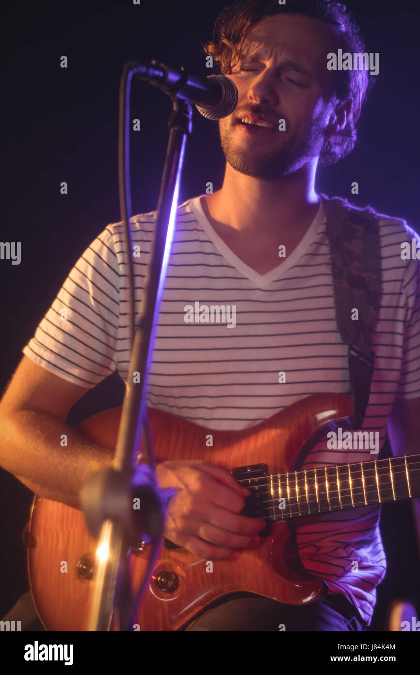 Male singer playing guitar while performing in music concert Stock ...