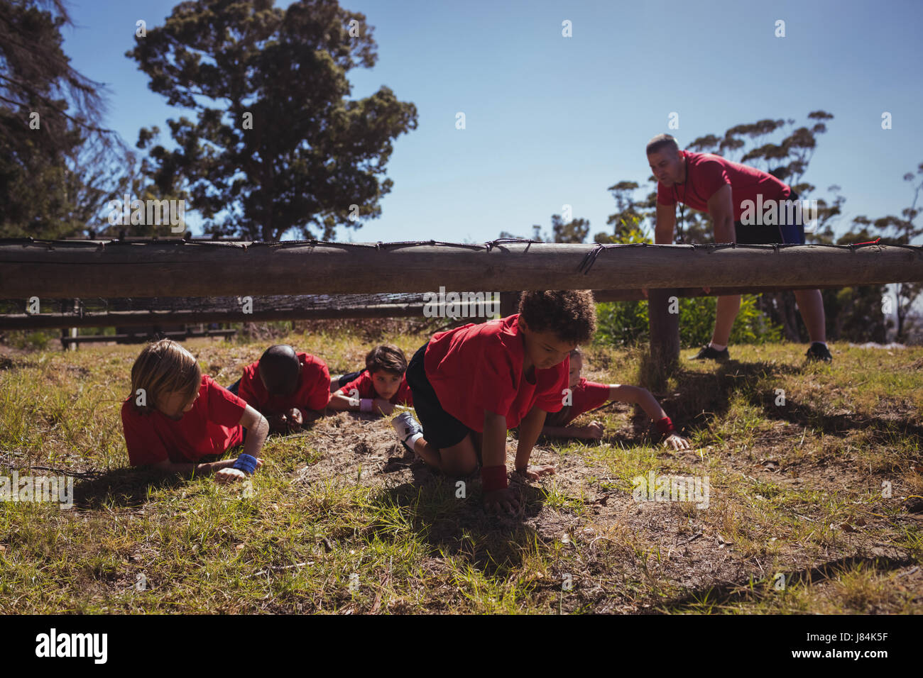 Kids crawling under the net during obstacle course training in the boot ...