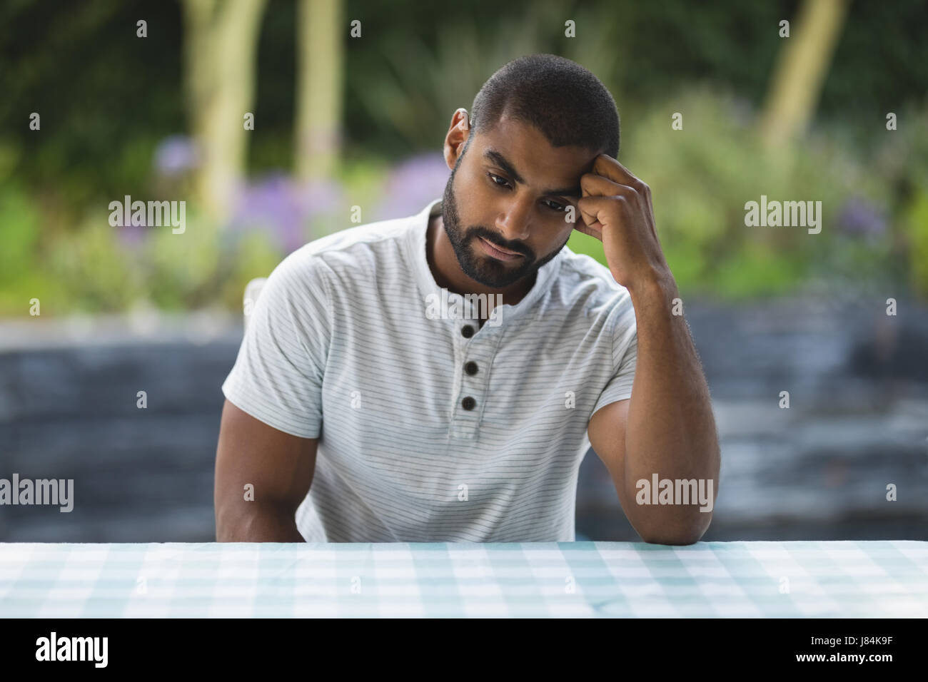 Upset man leaning on table at patio Stock Photo - Alamy