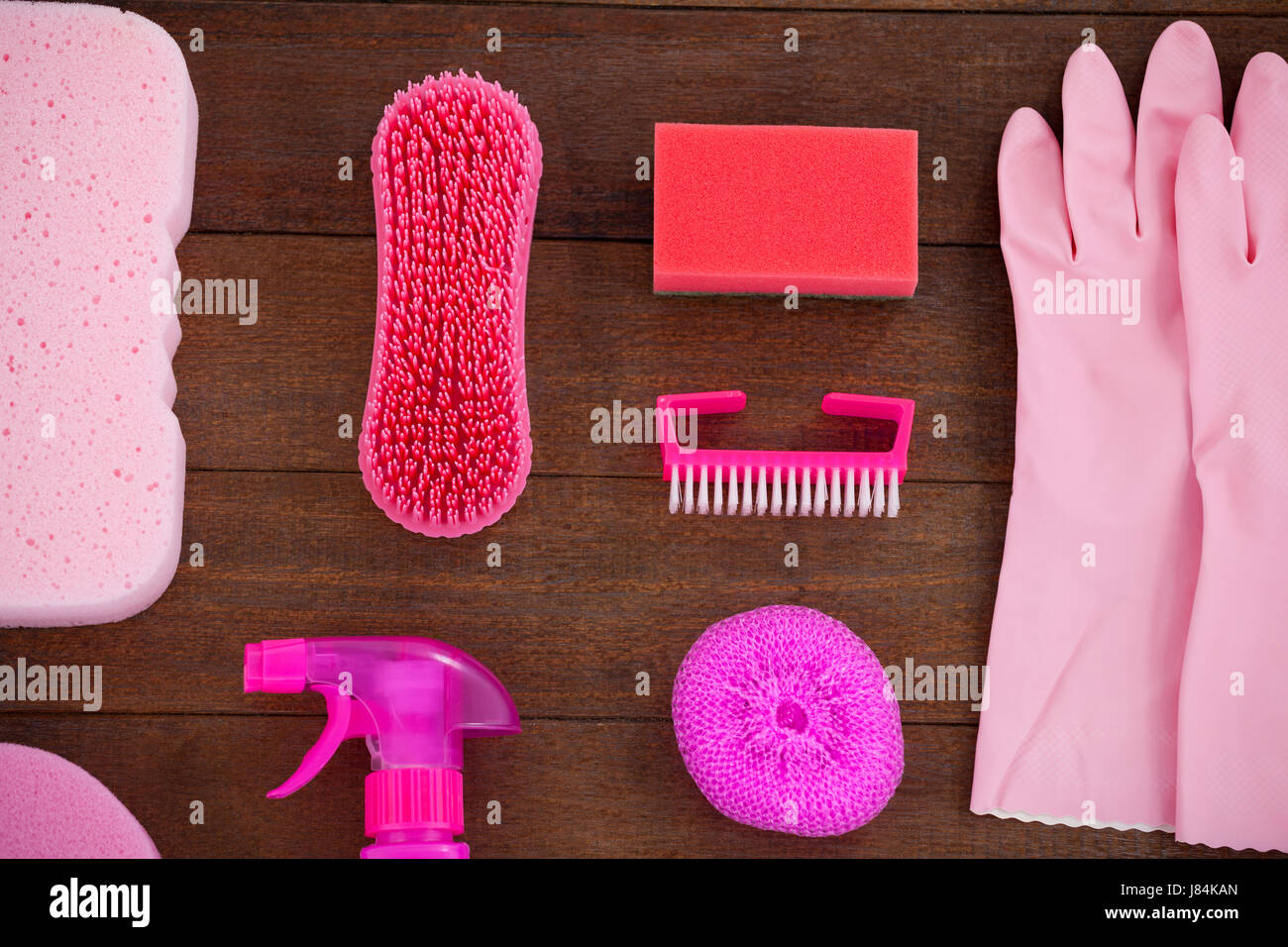 Close-up of pink color cleaning equipment arranged on wooden floor ...