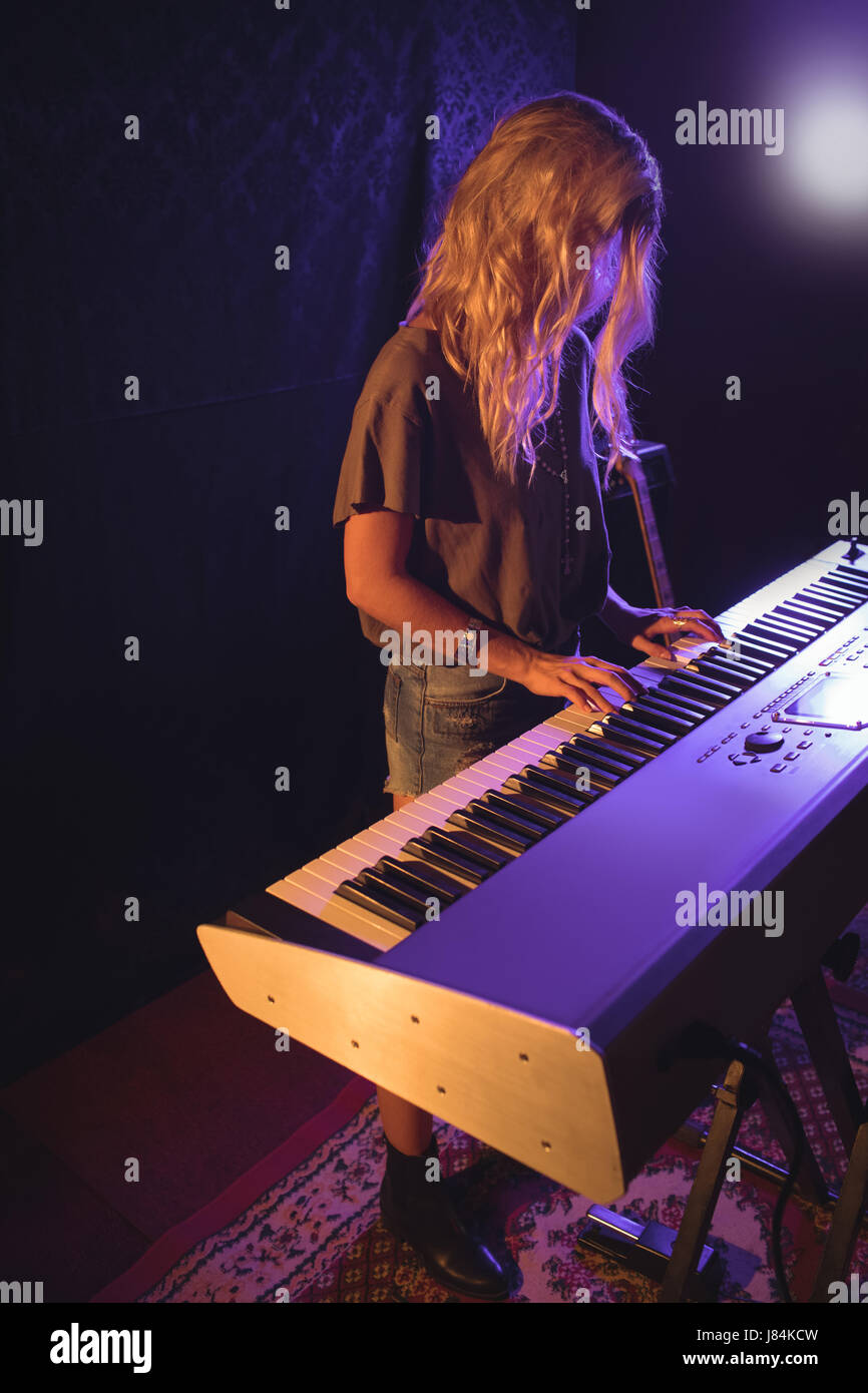 Confident female musician playing piano in illuminated nightclub Stock ...