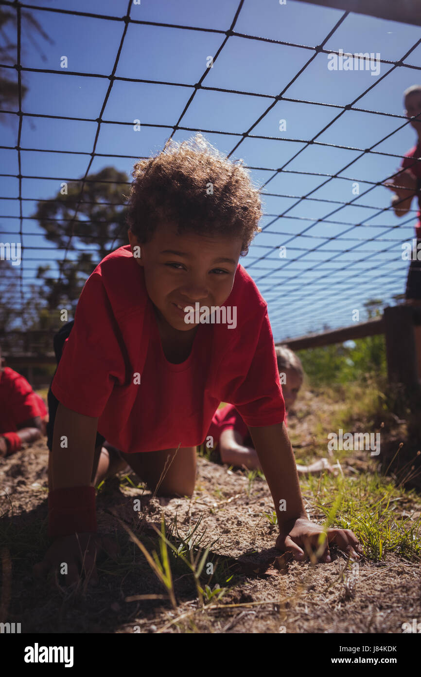 Boy crawling under the net during obstacle course training in the boot ...