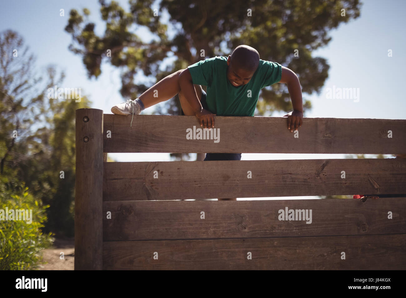 Boy climbing wooden wall during obstacle course in boot camp Stock ...