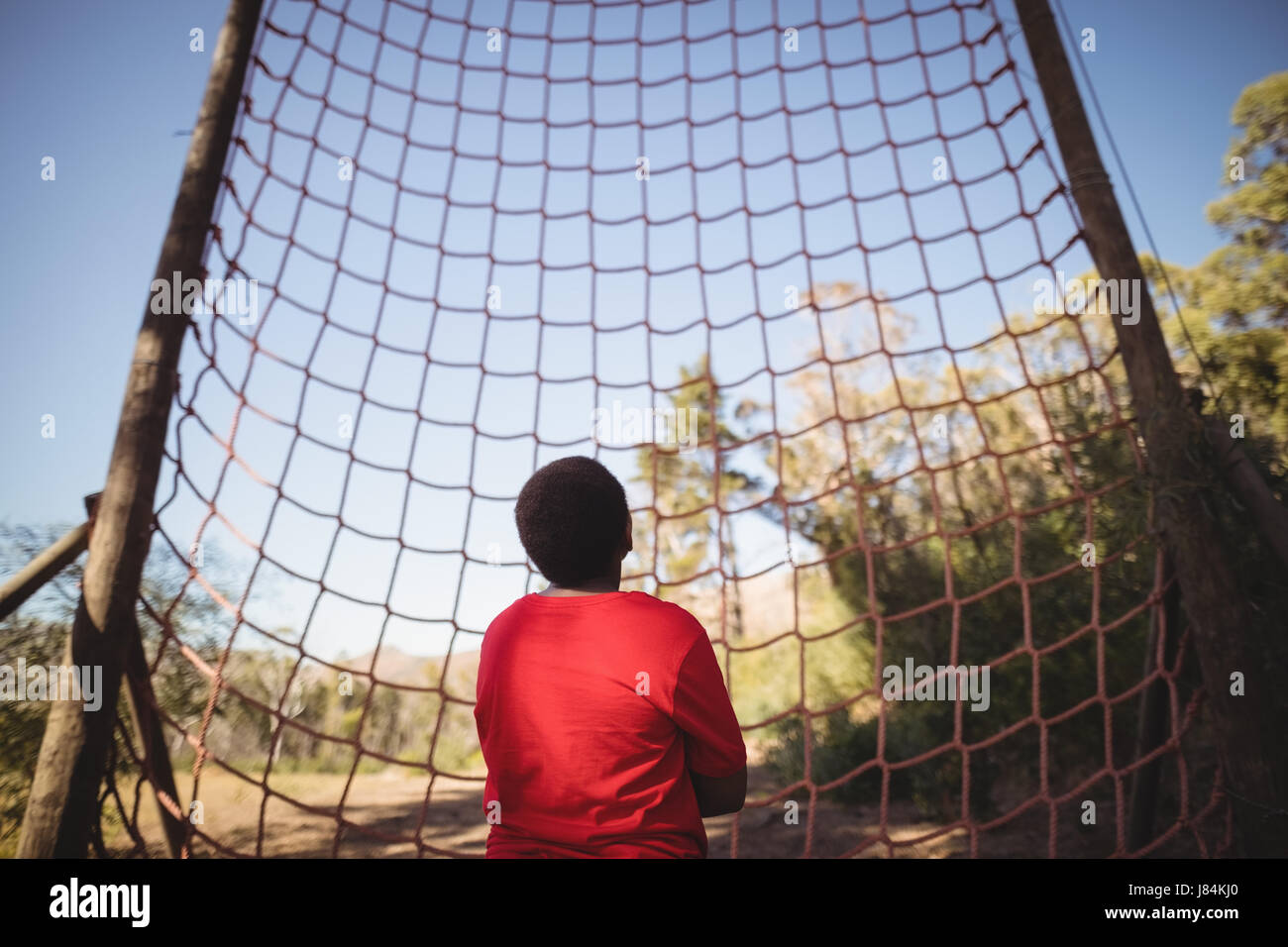 Rear view of kid looking at net during obstacle course in boot camp ...