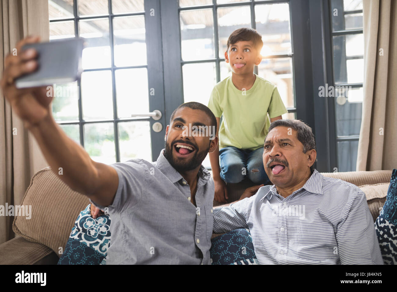 Happy multi-generation family making face while taking selfie together ...