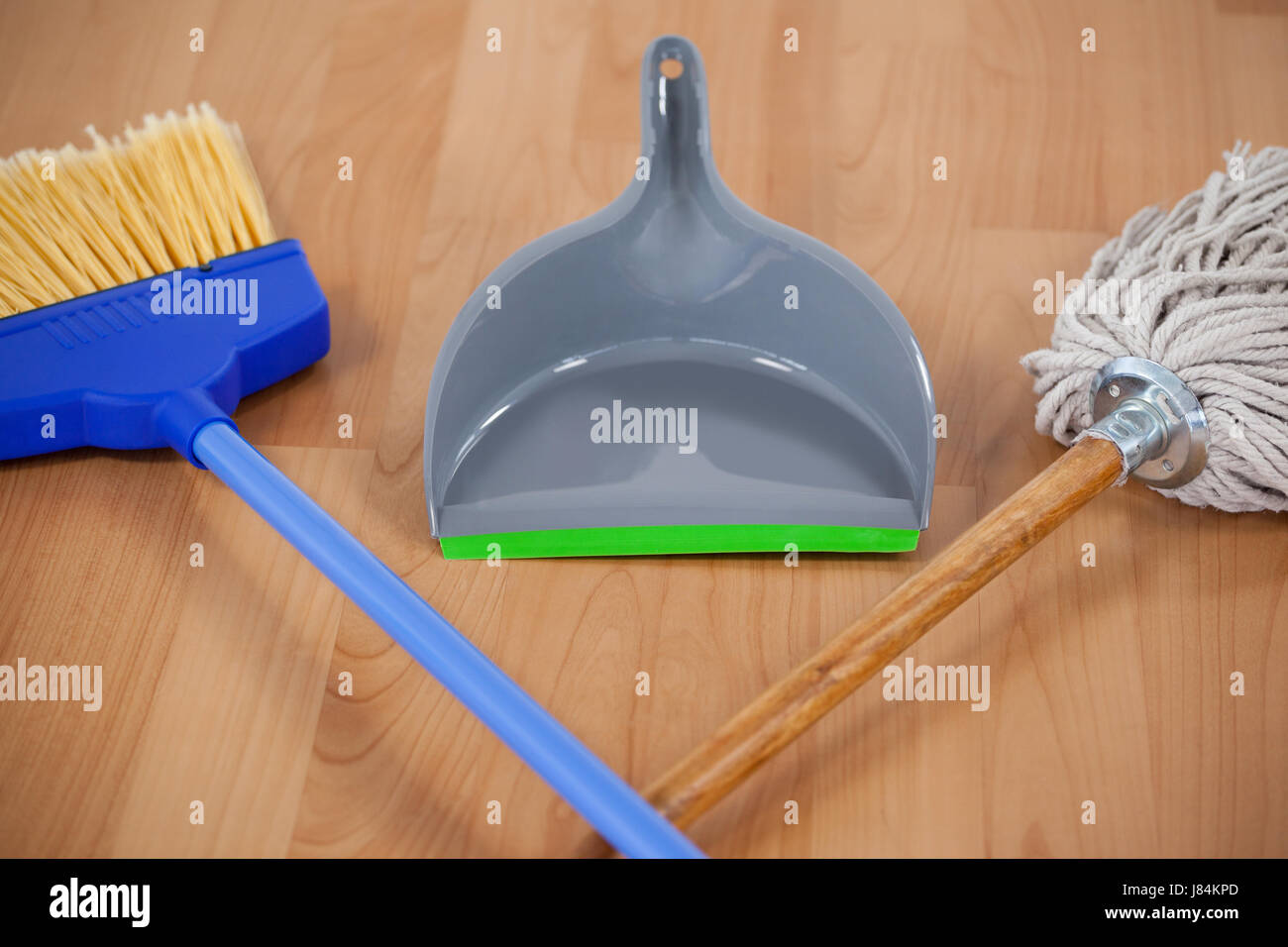 Close-up of dustpan, sweeping broom and mop on wooden floor Stock Photo ...
