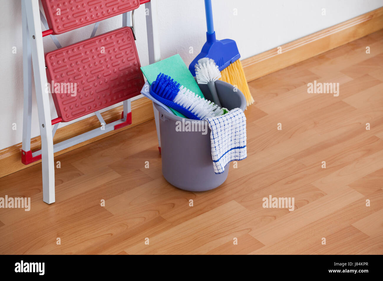 Ladder and cleaning equipment on wooden floor against wall Stock Photo ...