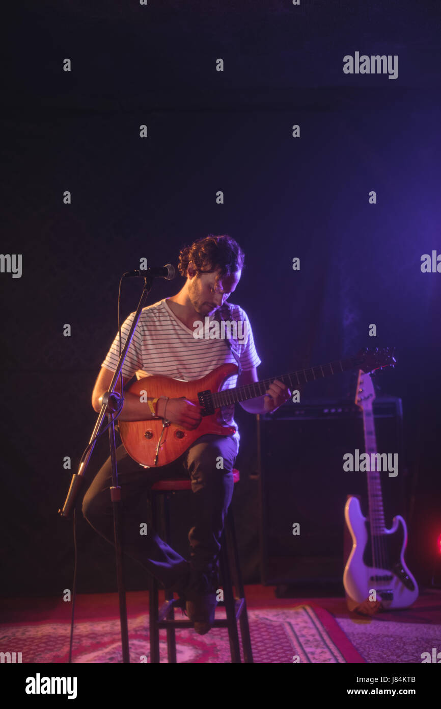 Full length of confident singer playing guitar while performing in ...