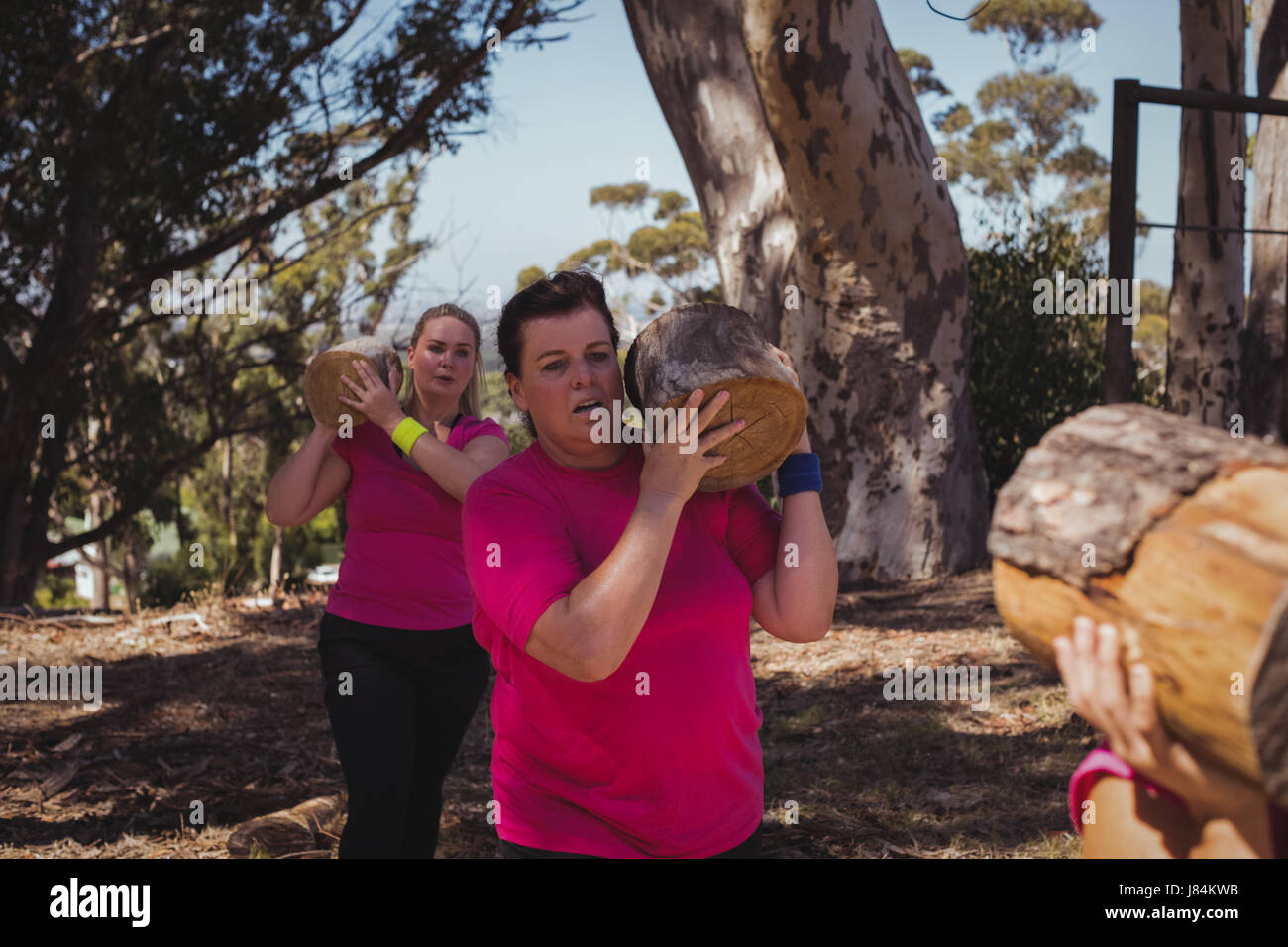 Group of women carrying a heavy wooden log during obstacle course in ...