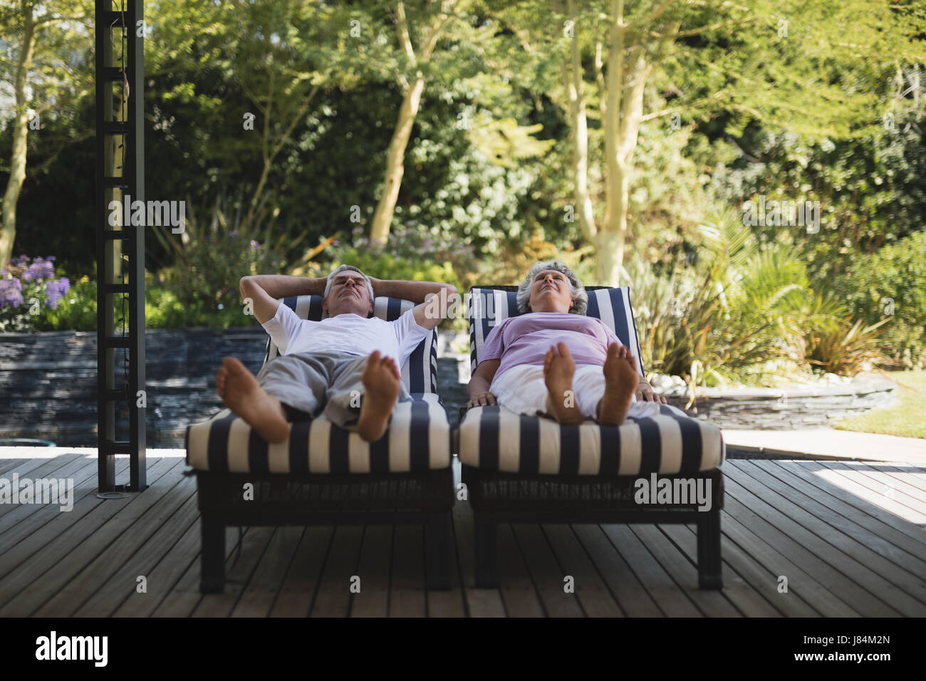 Full length of senior couple resting on lounge chairs at porch Stock ...