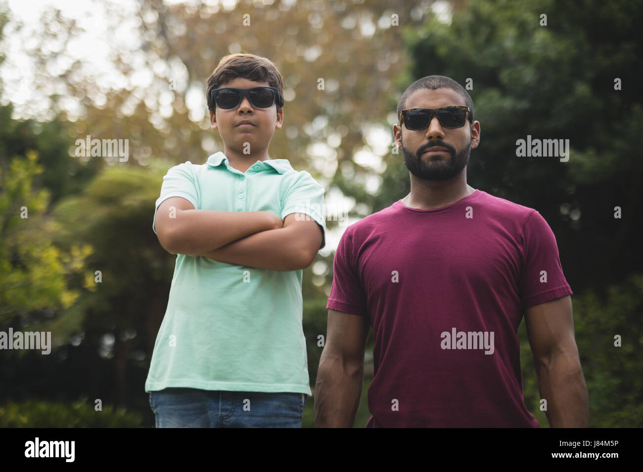 Confident father and son wearing sunglasses while standing at park ...