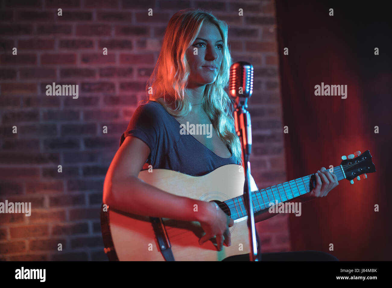 Confident female singer playing guitar in nightclub Stock Photo - Alamy