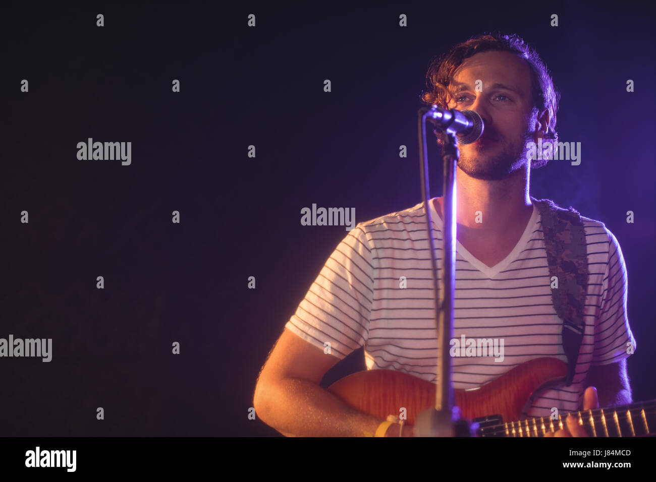 Confident male singer performing with guitar in concert Stock Photo - Alamy
