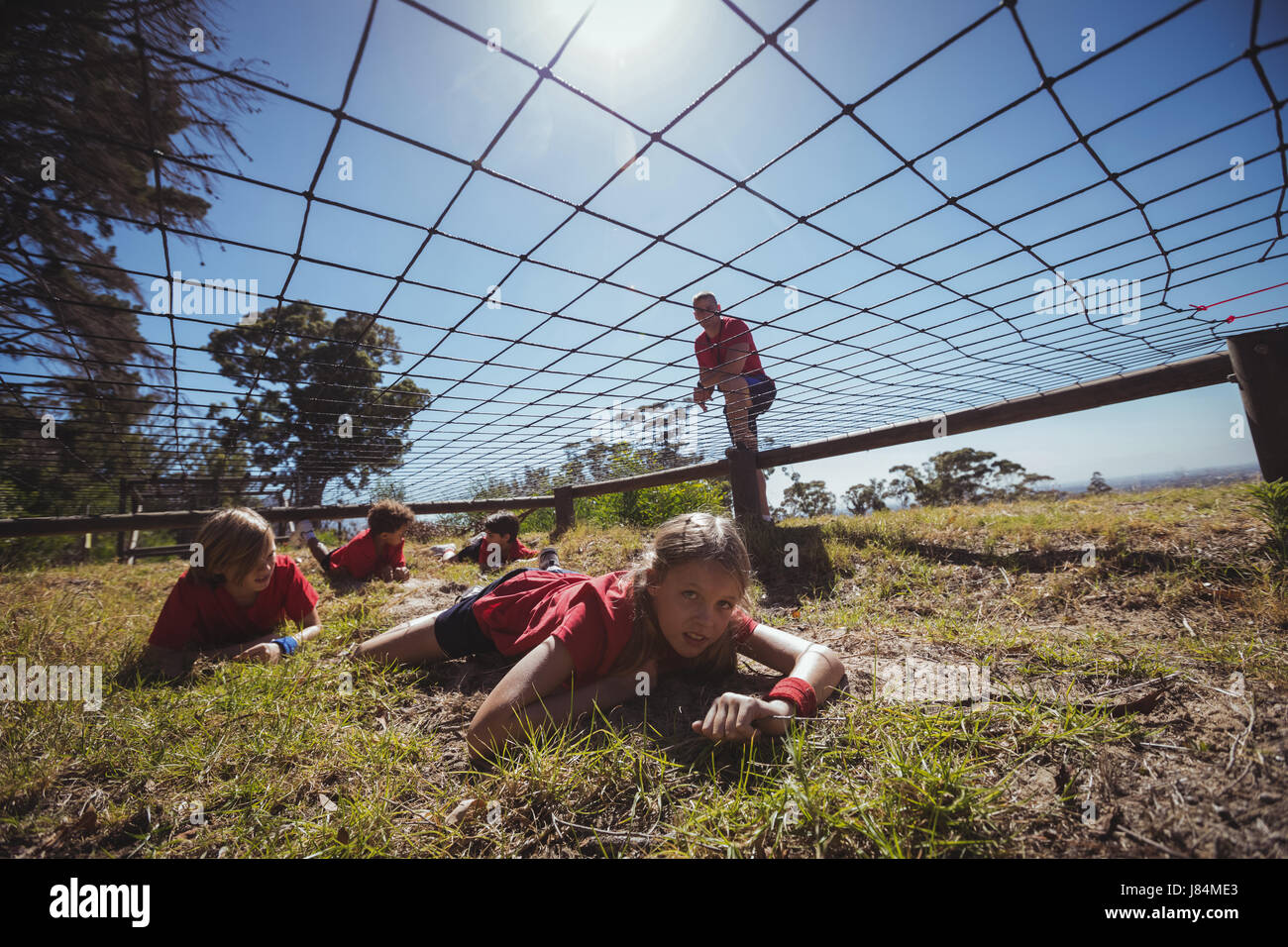 Kids crawling under the net during obstacle course training in the boot ...