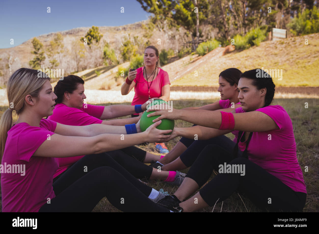 Female trainer instructing women while exercising in the boot camp on a ...