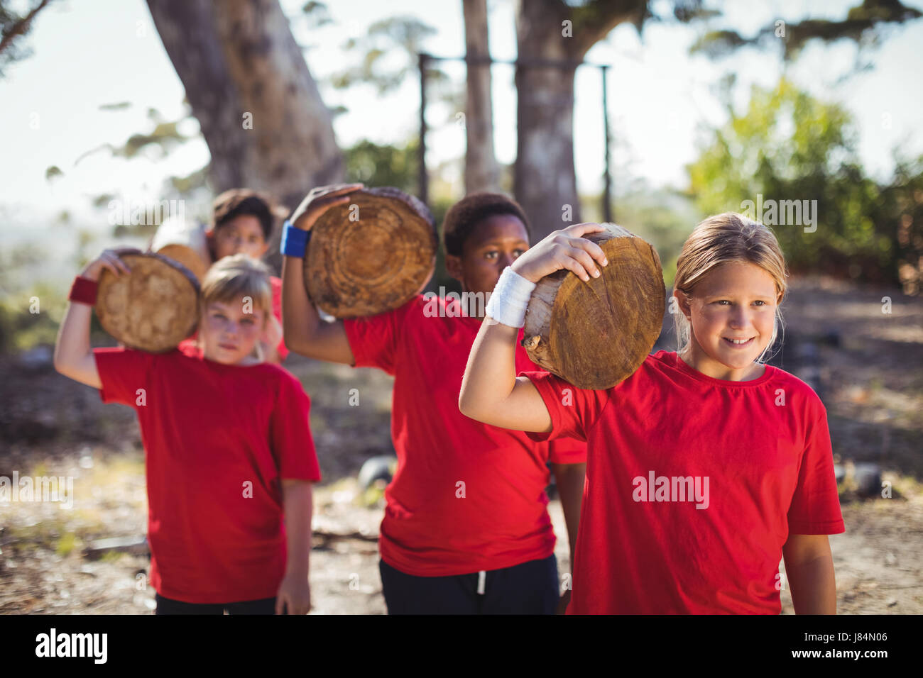 Kids carrying wooden log during obstacle course training in the boot ...