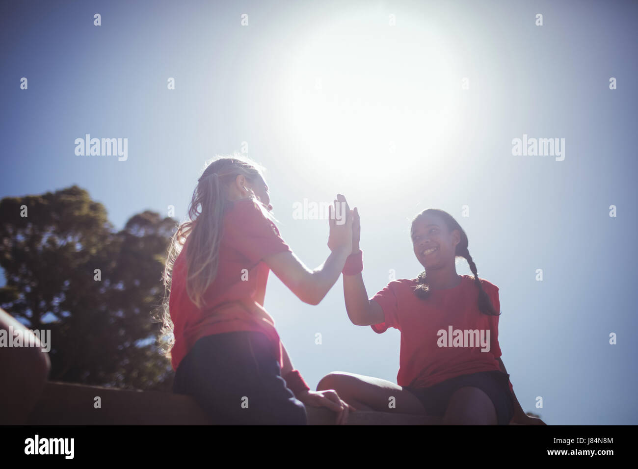 Two girl giving high five to each other during obstacle course training ...