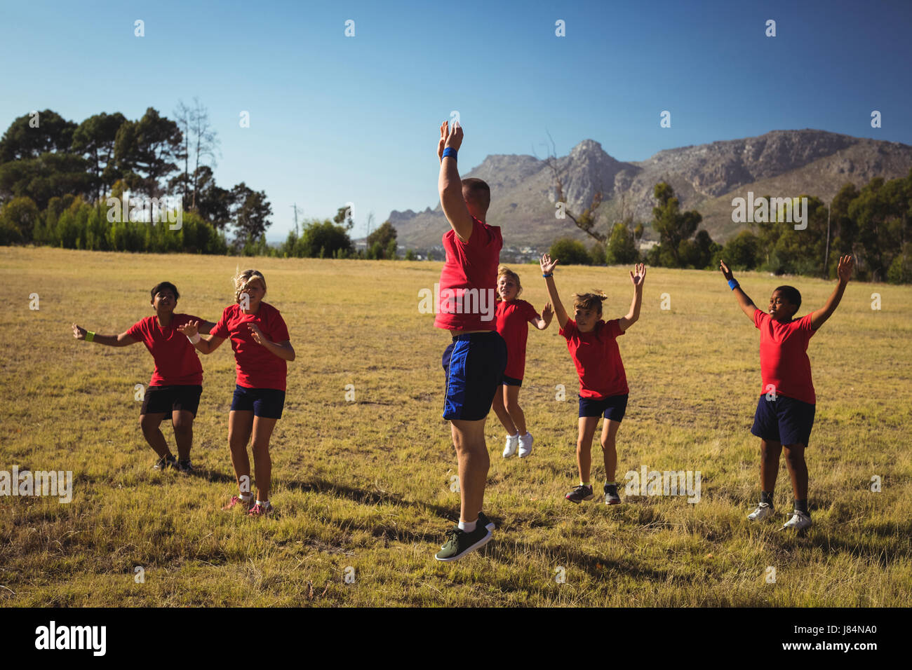 Trainer training kids in the boot camp on a sunny day Stock Photo - Alamy
