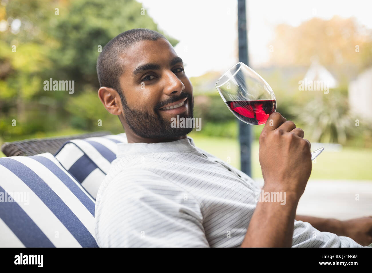 Portrait of smiling man drinking red wine while relaxing at porch Stock ...