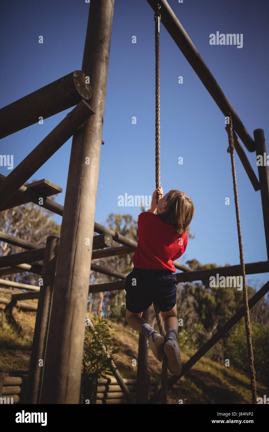 Determined girl climbing rope during obstacle course in boot camp Stock ...